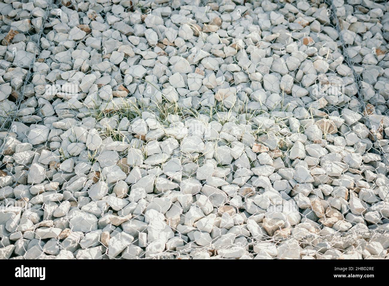 Granite stones behind a metal grate for strengthening the slope. Stones ...