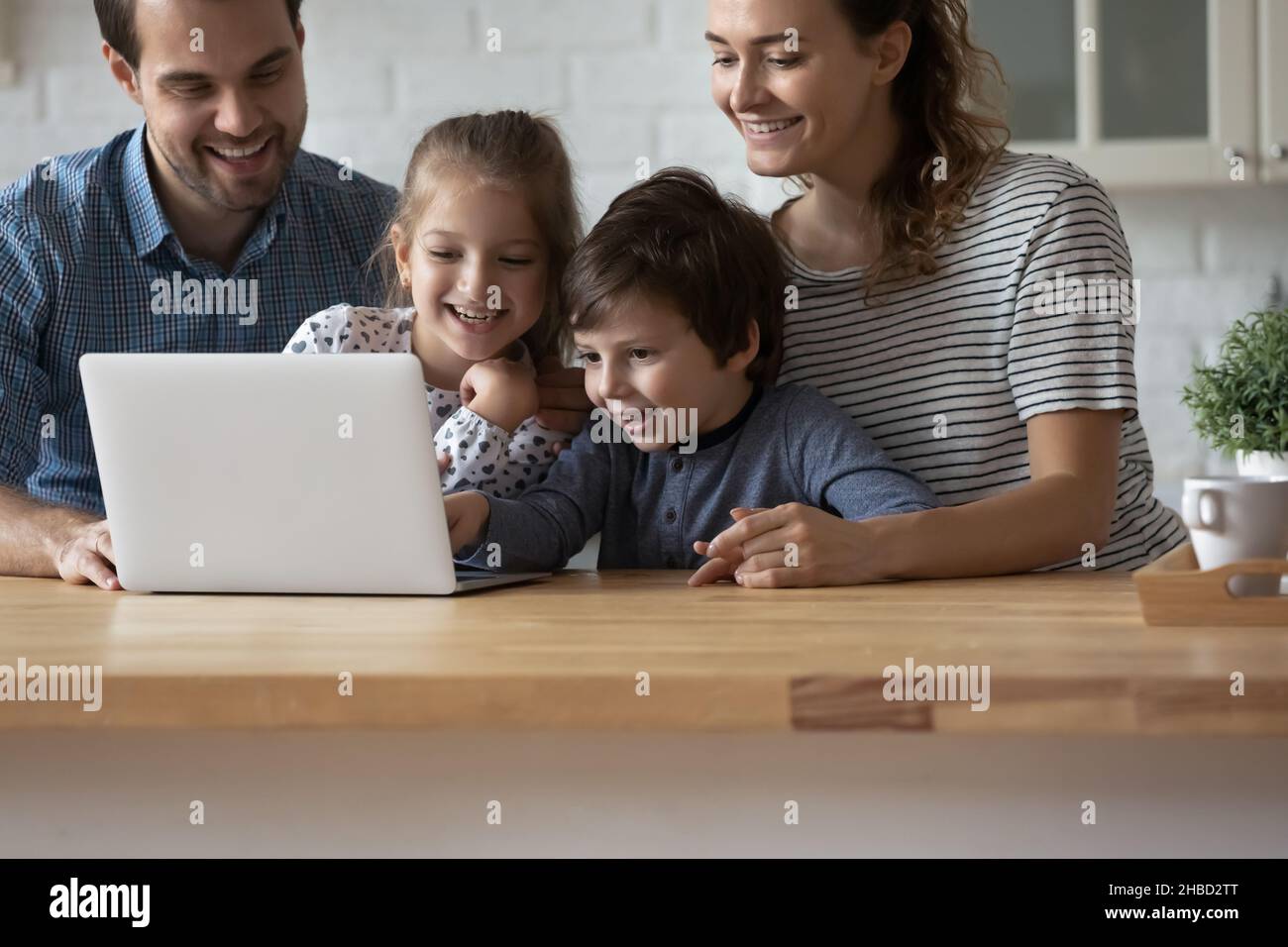 Happy parents with two kids using laptop at home together Stock Photo ...