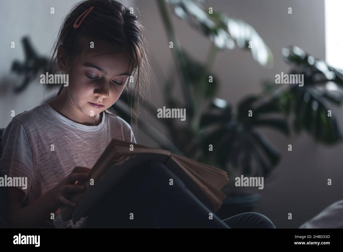 A little girl uses the phone, holding a book in her hands Stock Photo ...