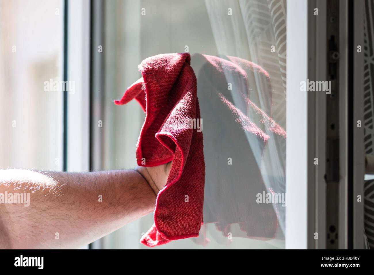 A man wiping window using red microfiber rug - housekeeping concept ...