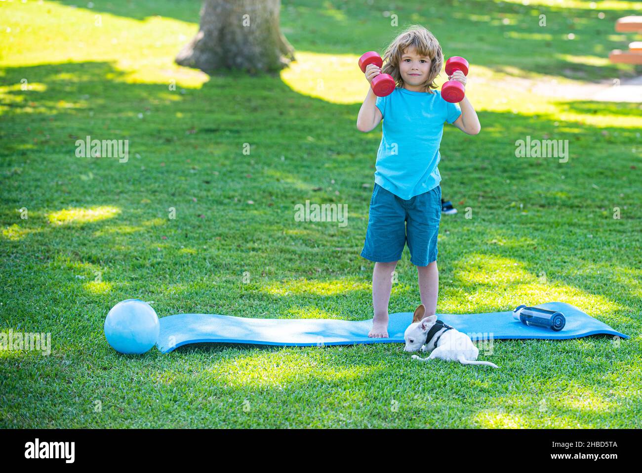 Fitness child. Portrait of sporty little boy with dumbbells in park ...