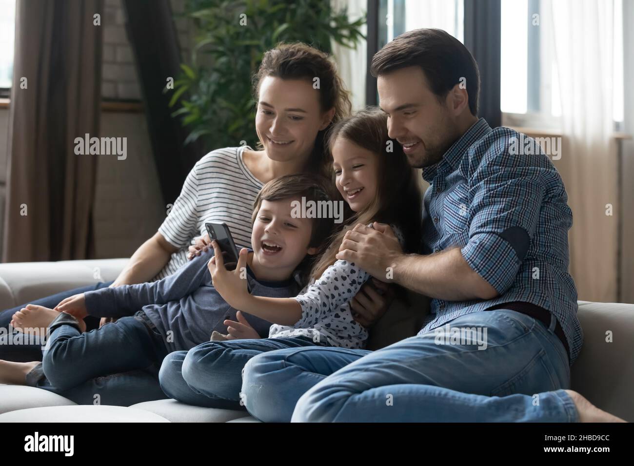 Happy young parents with kids using smartphone at home together Stock ...