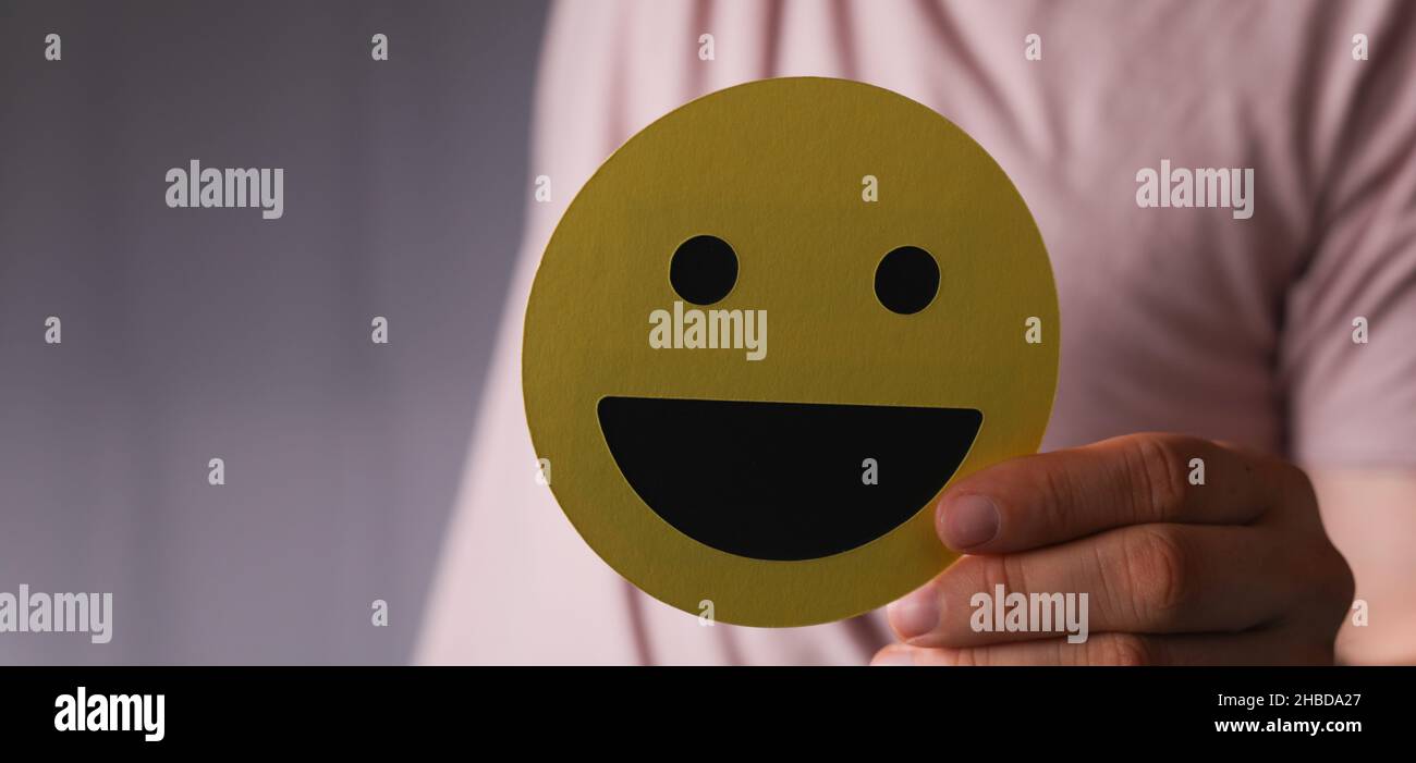 A male holding a smile emoji Stock Photo - Alamy