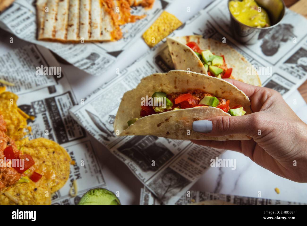 Female hands hold Mexican beef tacos with vegetables on restaurant ...