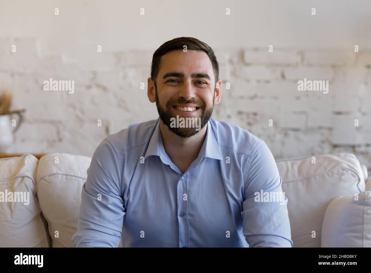 Portrait of smiling young man sitting on couch Stock Photo - Alamy
