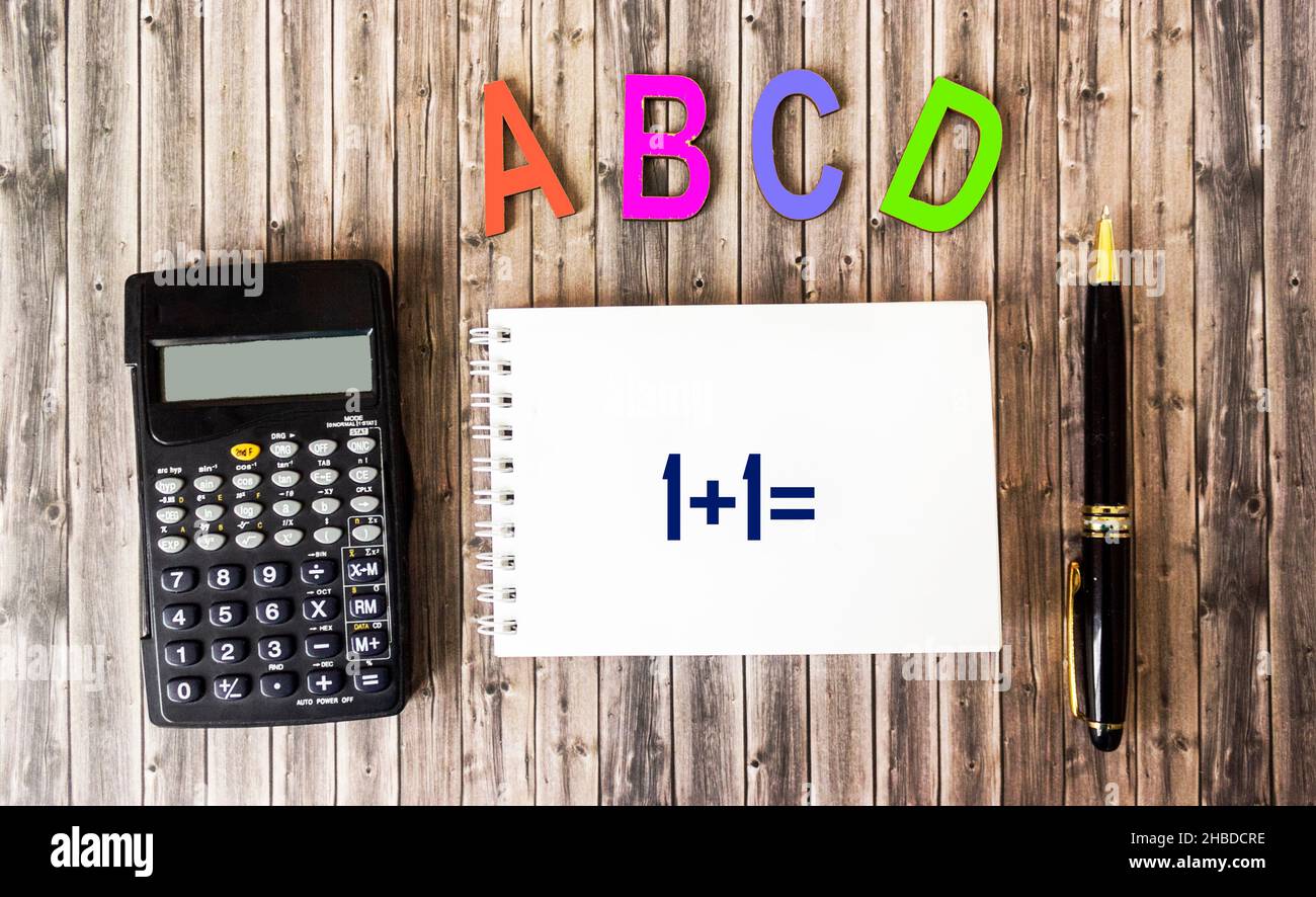 One plus one equals, written on a notepad and a wooden background ...