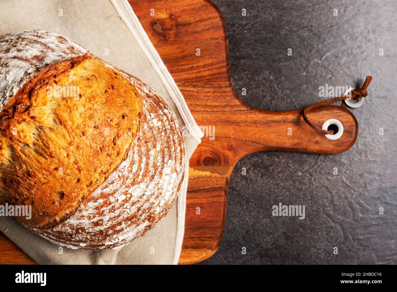 Wholemeal sourdough bread on brown chopping board. Warm mood, concept ...