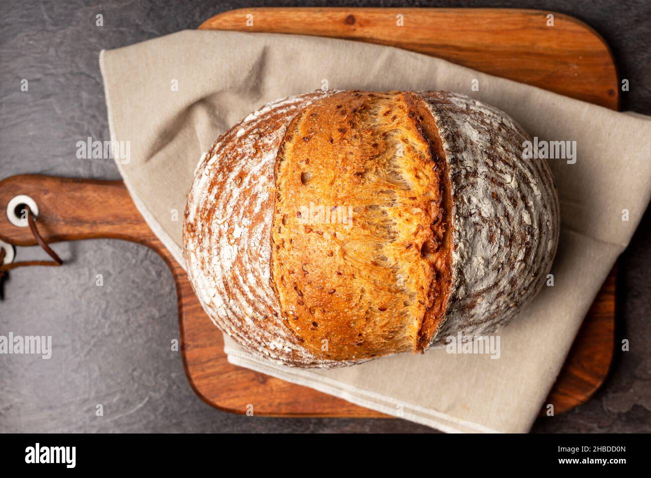Wholemeal sourdough bread on brown chopping board. Warm mood, concept ...