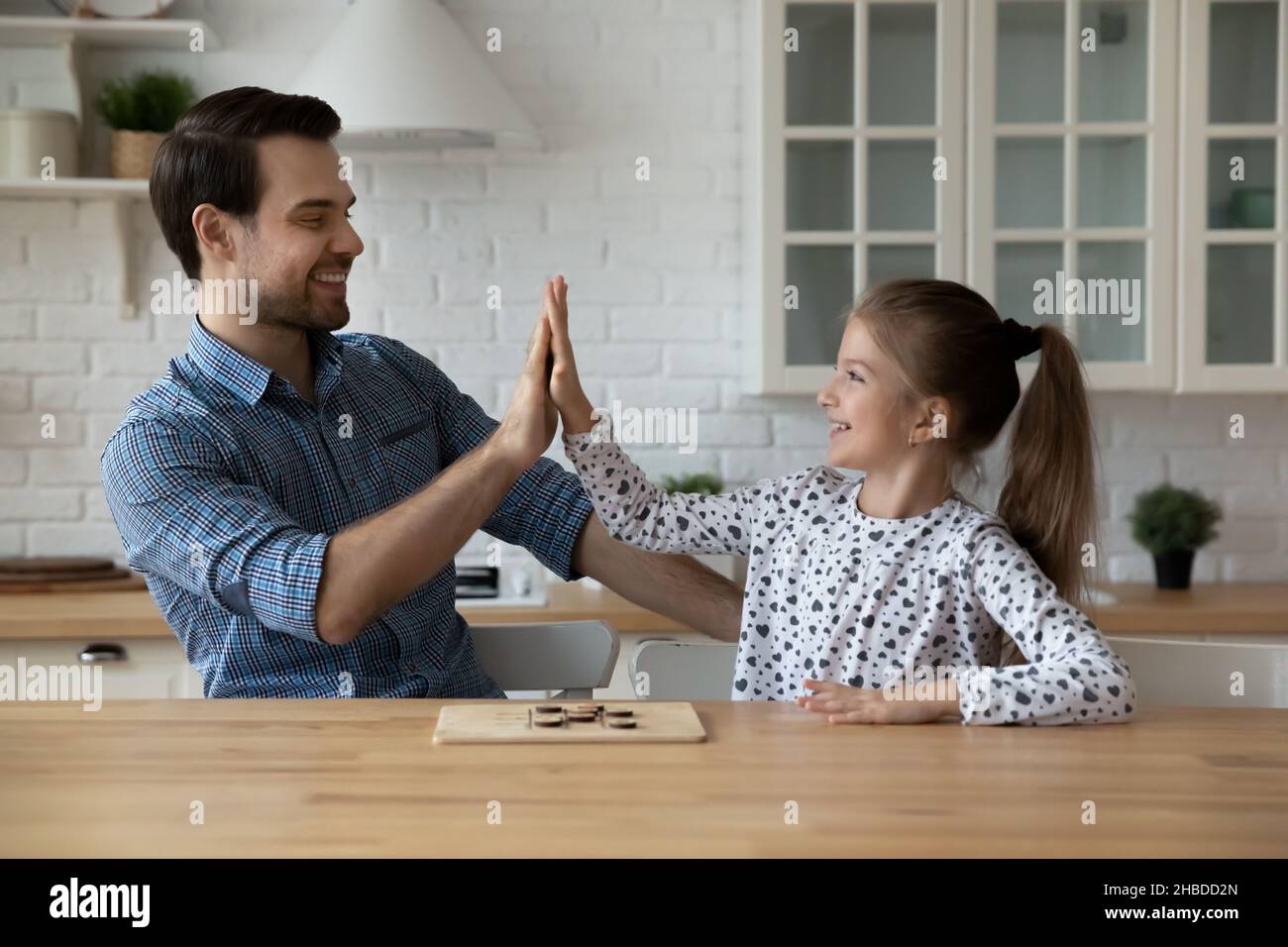 Happy father and daughter giving high five, playing board game Stock ...