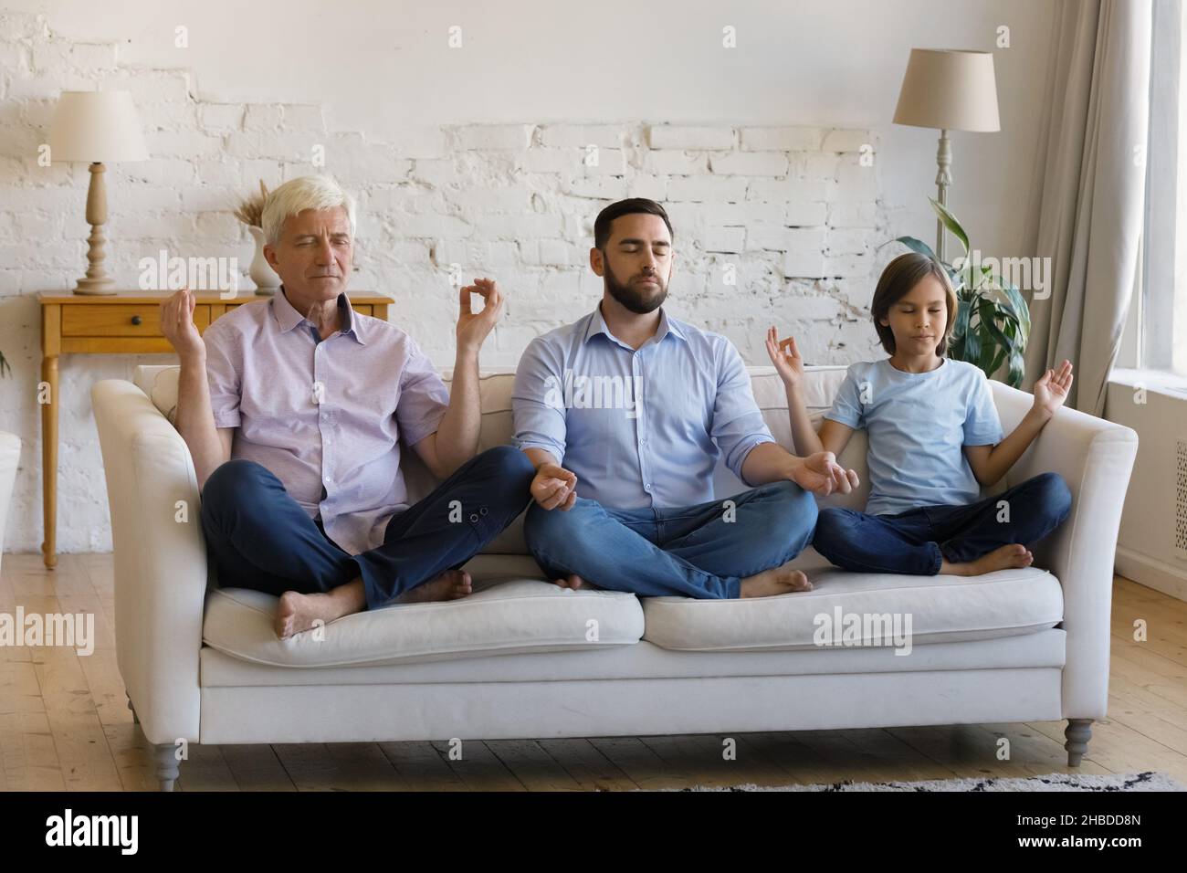 Happy relaxed three male generations family practicing yoga breathing ...