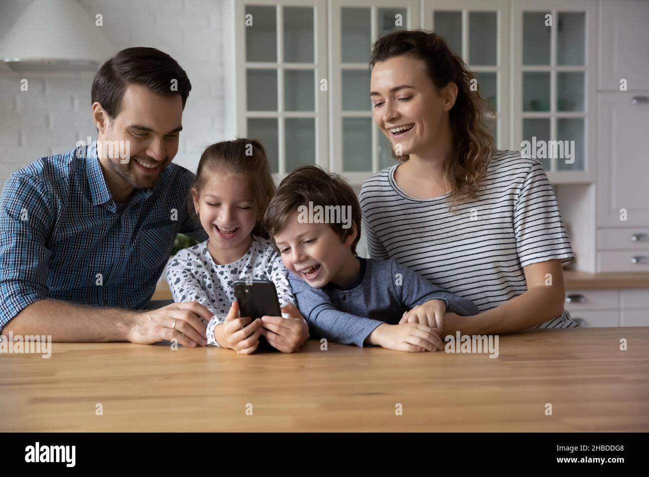 Happy parents with two kids using smartphone at home together Stock ...