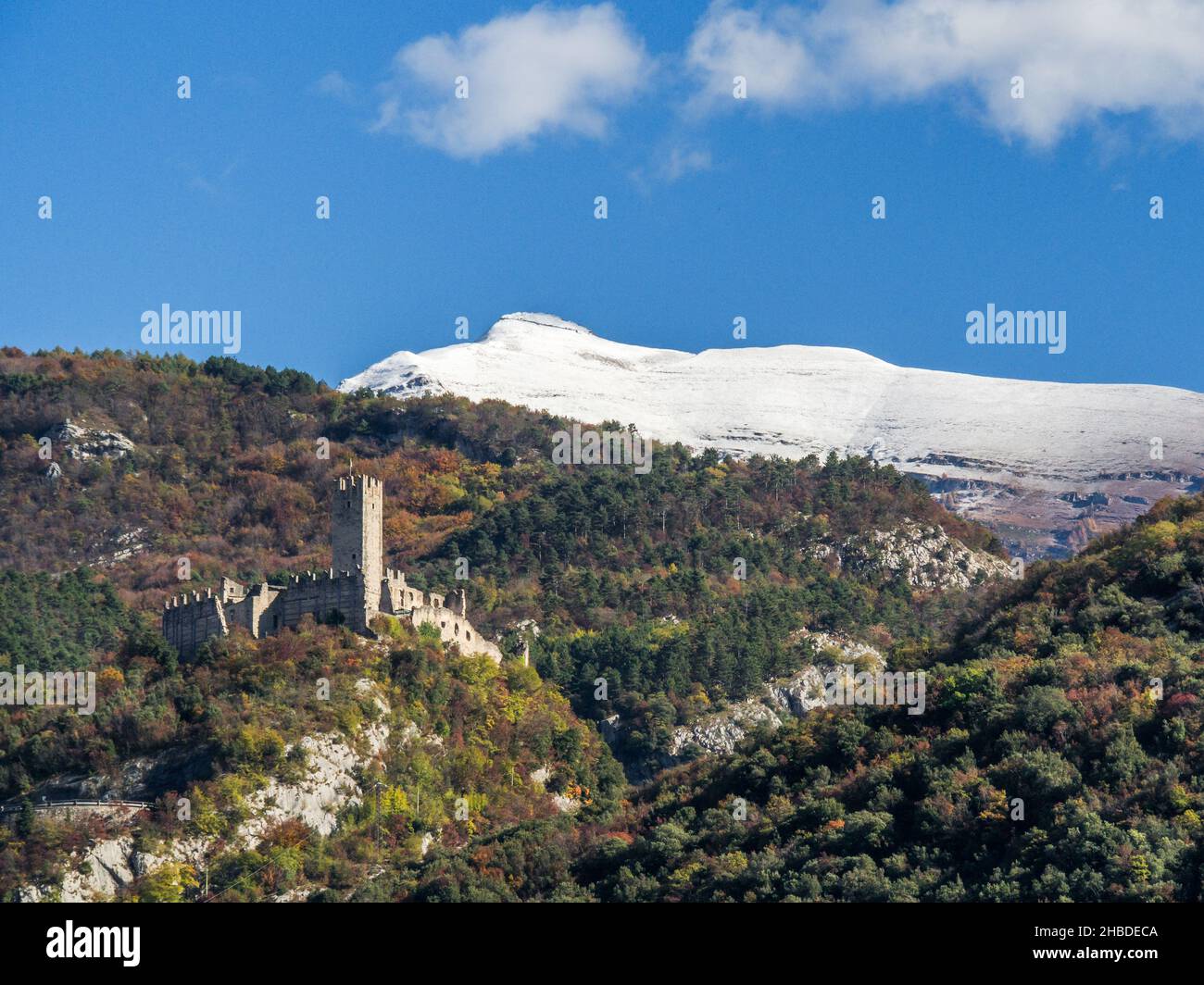 A scenic view of a Drena castle in the mountains covert with lush trees ...