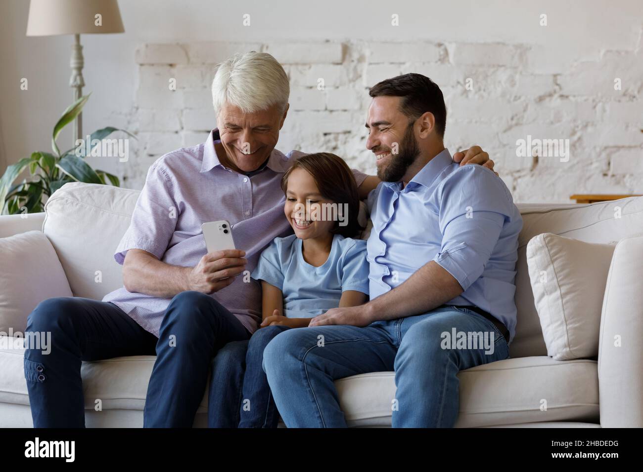 Happy three male generations family using cellphone apps at home Stock ...