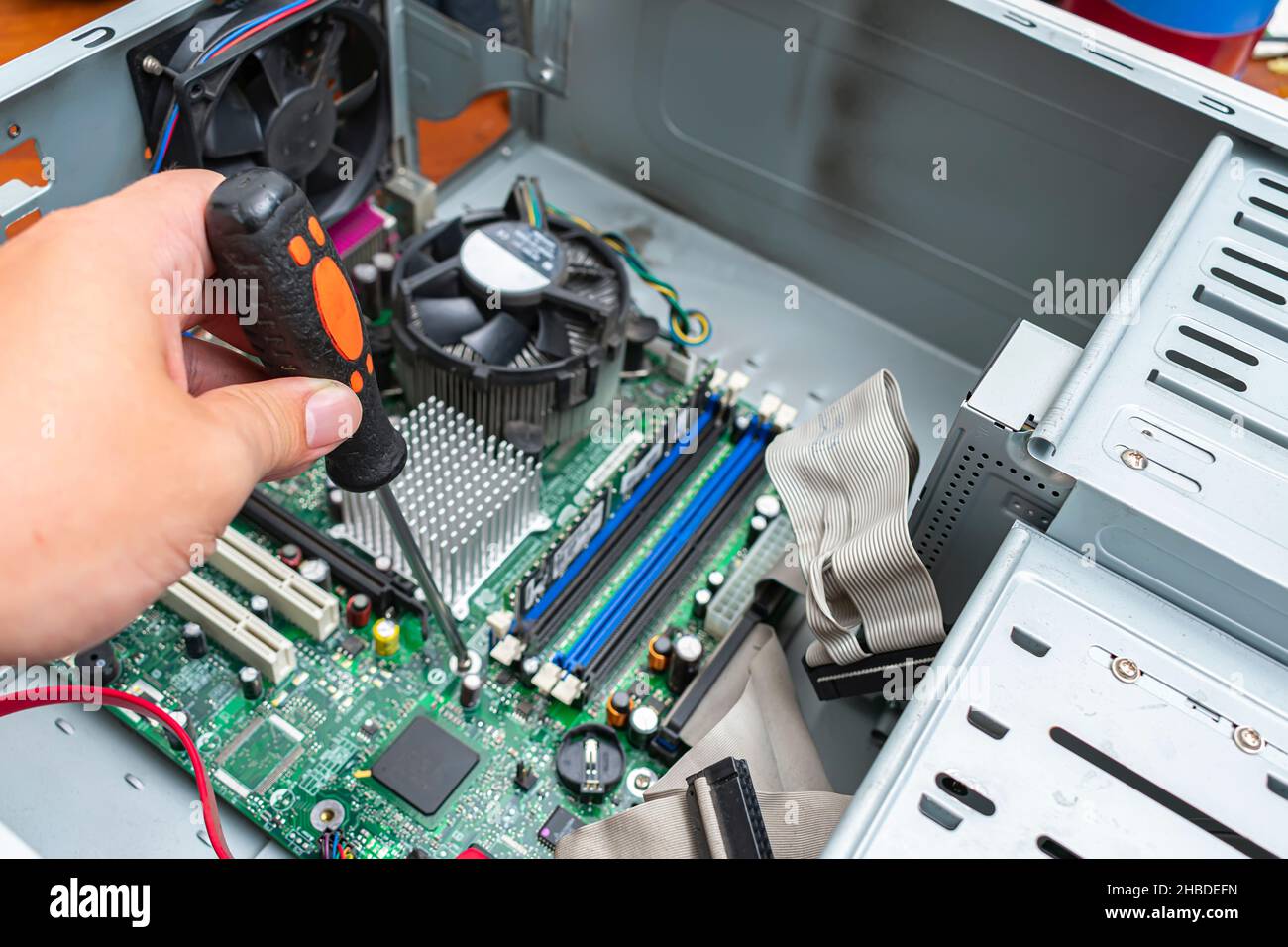 Computer repairman at work, unscrews the bolts with a screwdriver from ...