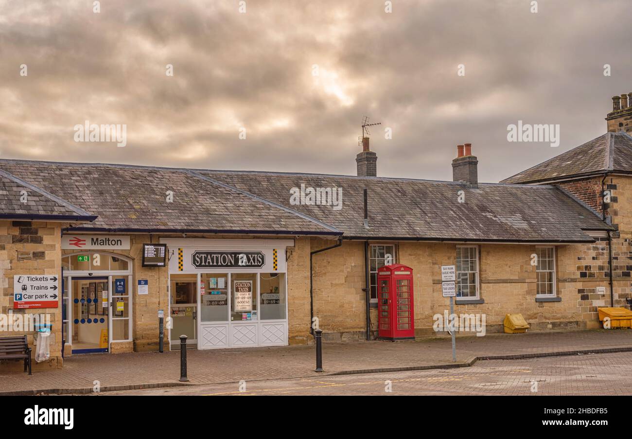 The entrance to a small railway station. An old red phone box is next ...