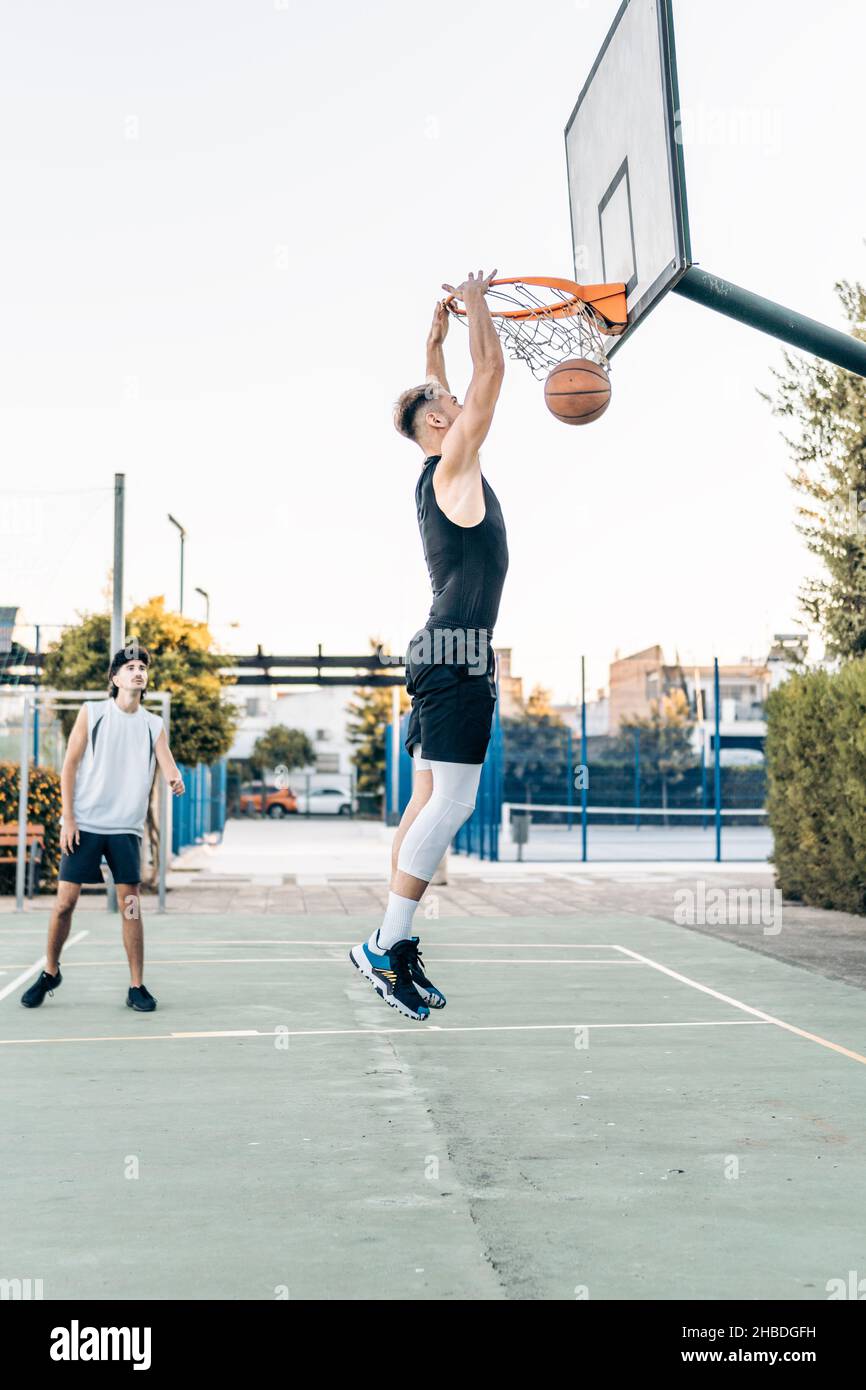 Man hanging from a basket as he scores in a friendly basketball match ...