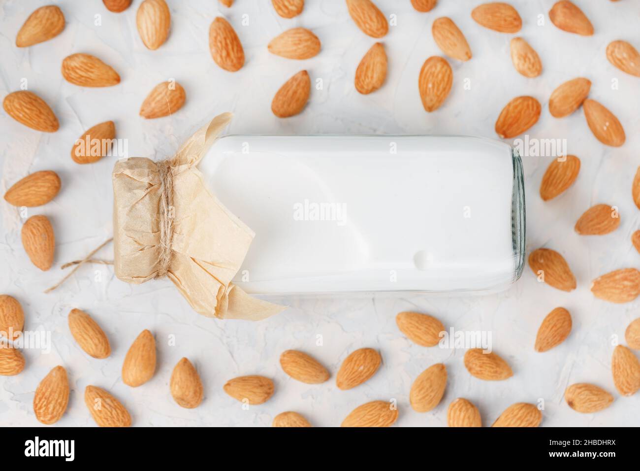 Almond milk in a bottle surrounded by a scattering of almond seeds on a ...