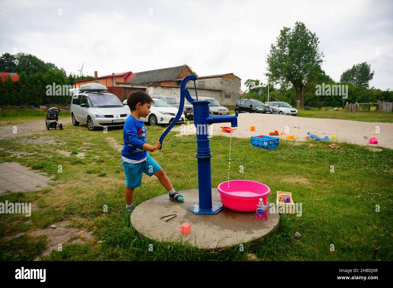 GLAPKI, POLAND - Jun 21, 2019: A young child pumping water with a pump ...