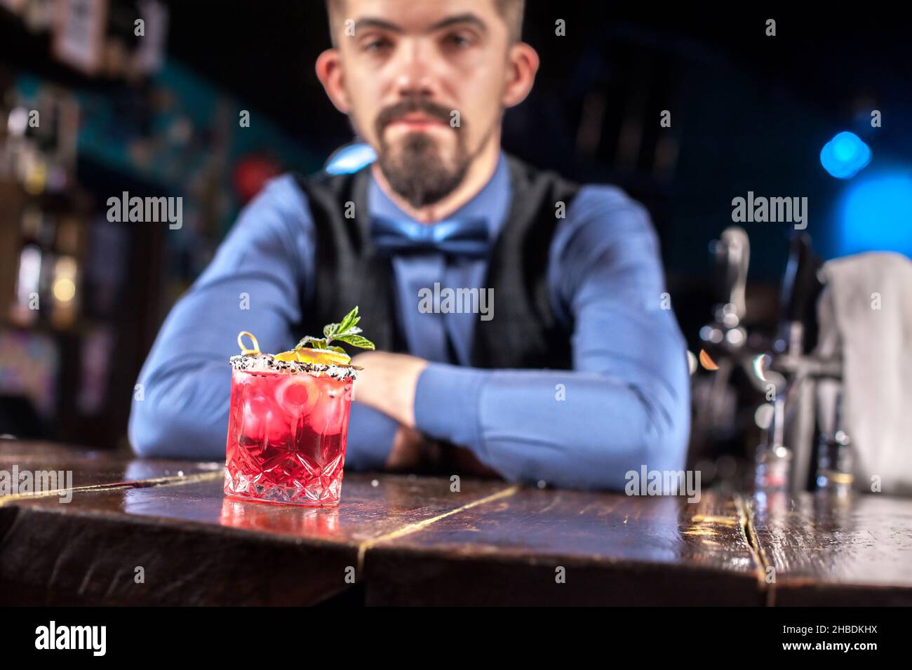 Professional barman places the finishing touches on a drink at bar ...