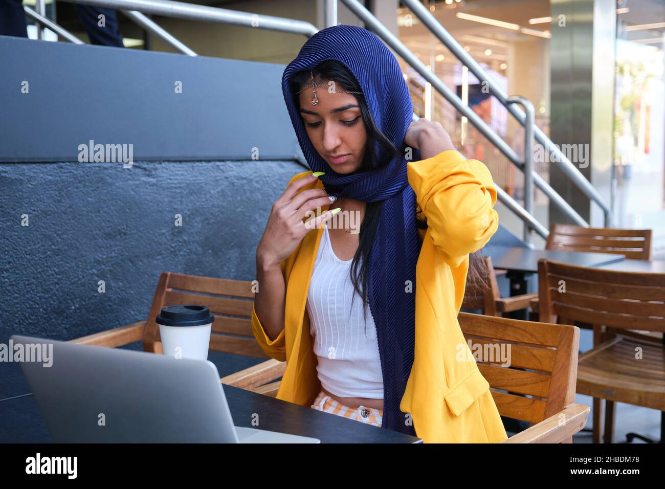 Young indian businesswoman wearing a scarf while working at a coffee ...