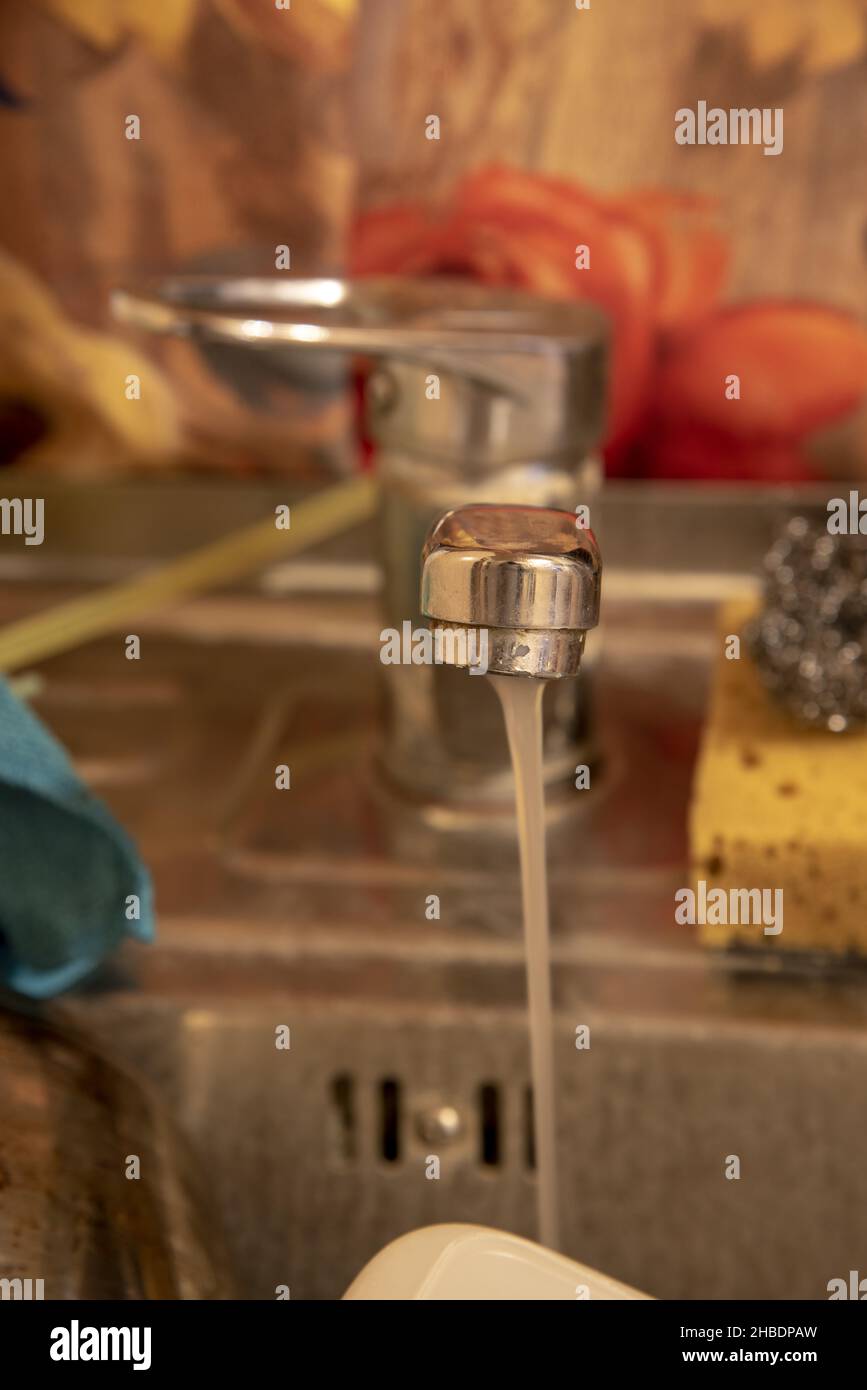 The water tap over the kitchen sink with dirty dishes. Focus on the ...