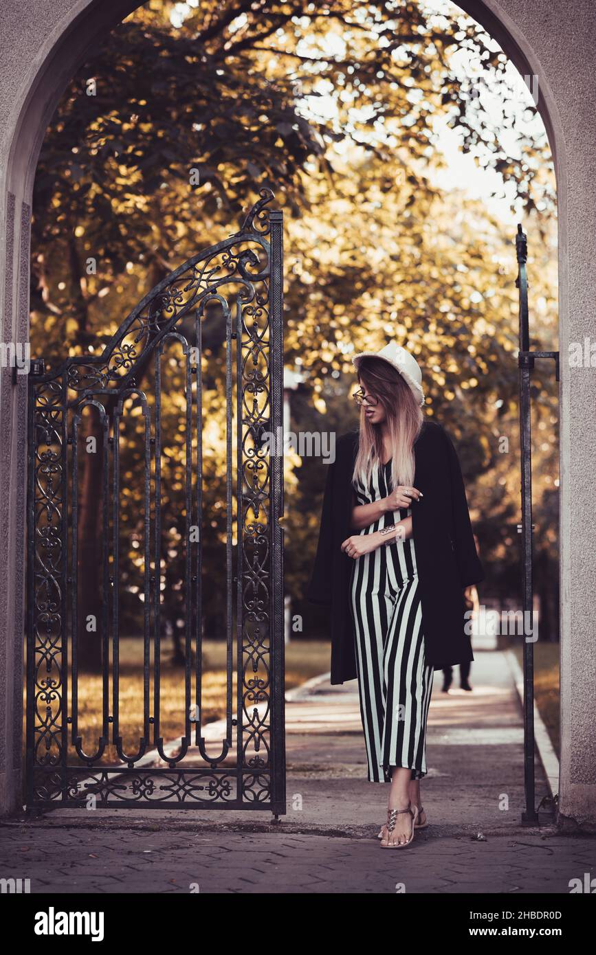 An attractive female with striped overalls and a black jacket passing ...