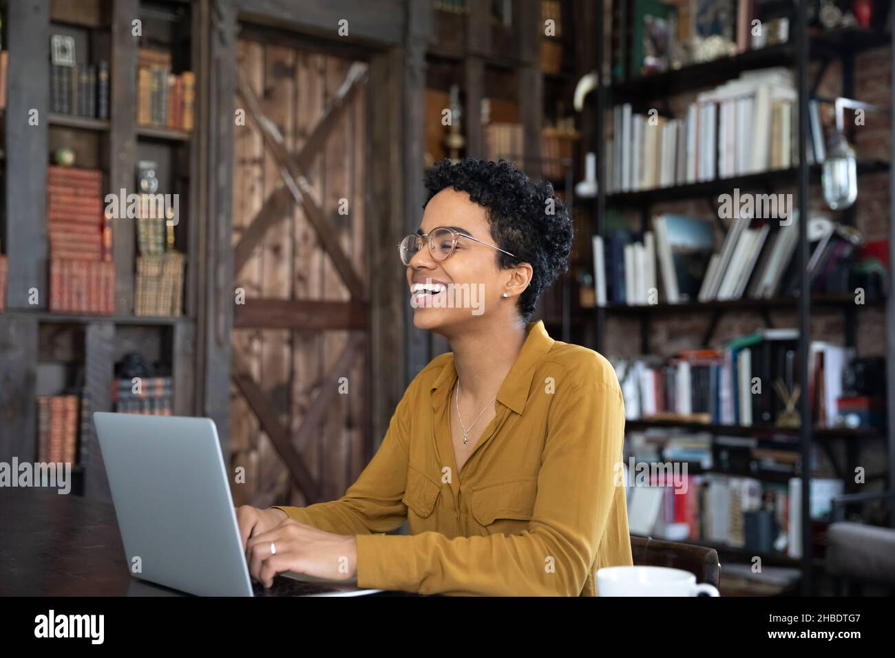 Happy young African American woman laughing looking at computer screen ...