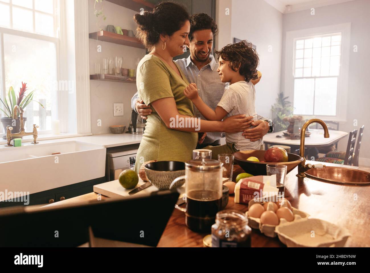 Bonding at breakfast time. Affectionate young family smiling happily ...