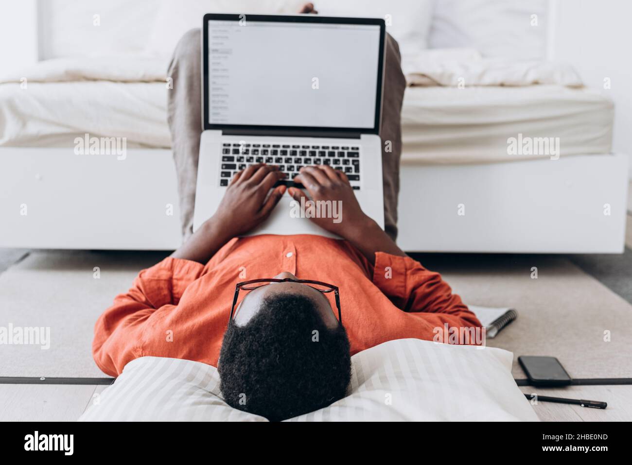 African-American man blogger in orange shirt and glasses works on ...