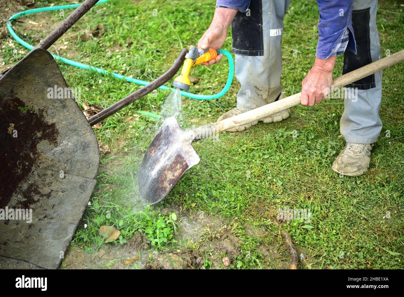 The mason rinses the concrete shovel with water from a hose Stock Photo ...