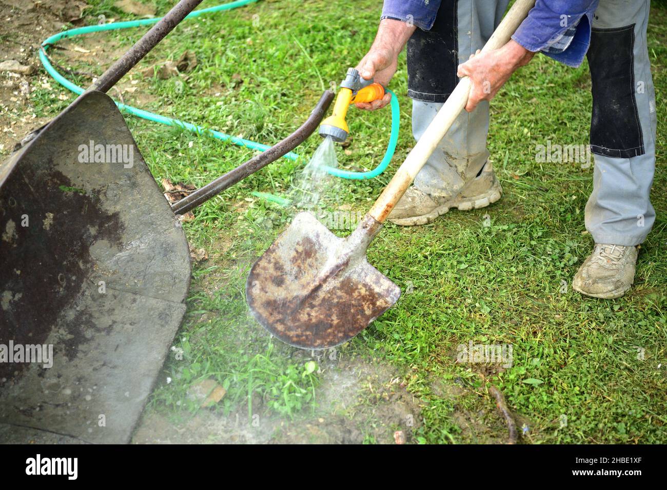 The mason rinses the concrete shovel with water from a hose Stock Photo ...