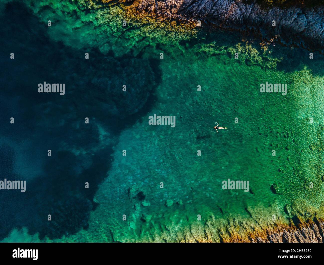 overhead view of woman floating on back in clear sea water greece ...