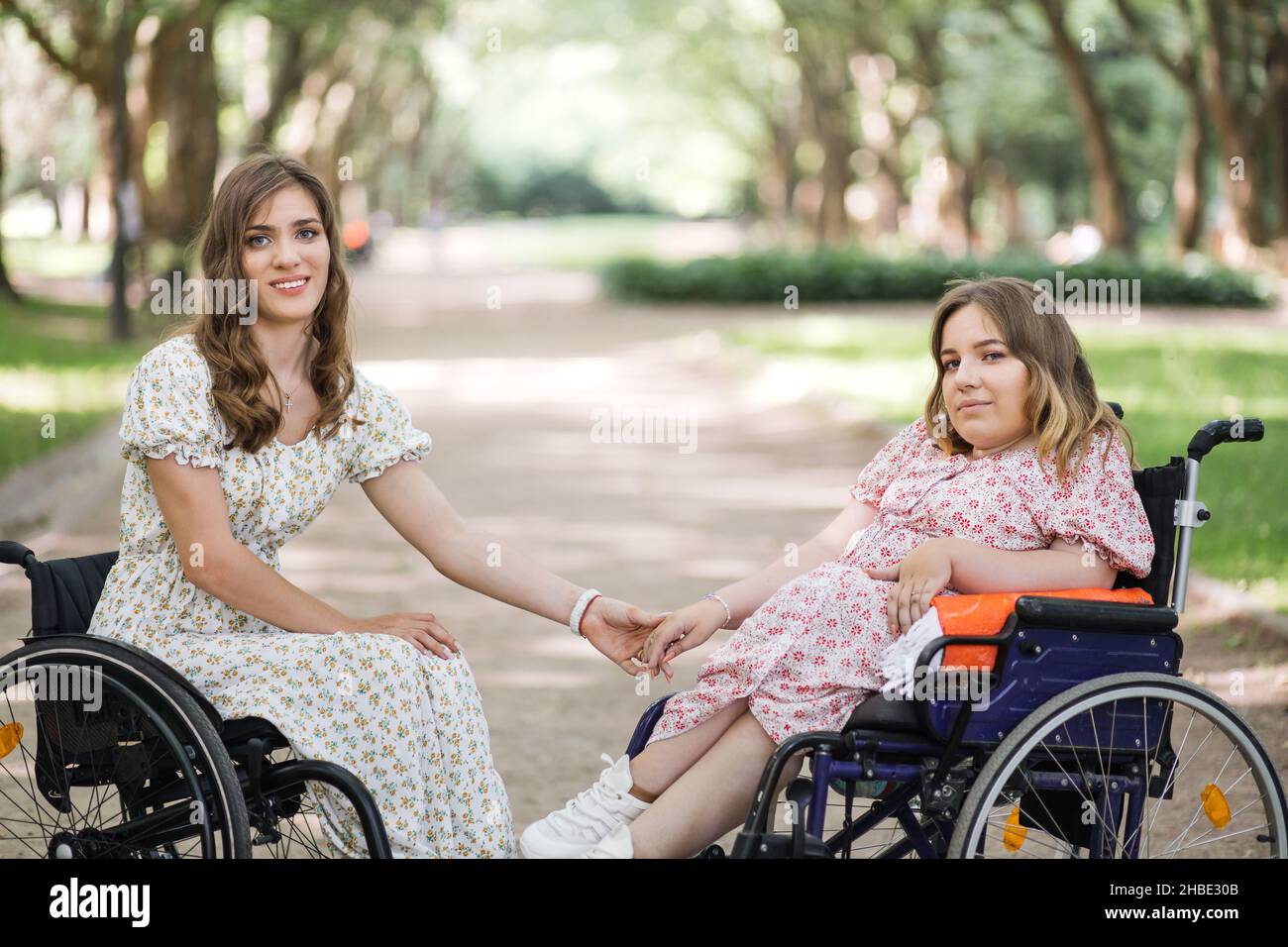 Pretty caucasian women in wheelchairs holding hands and smiling on ...
