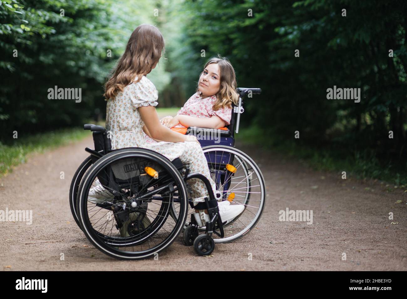 Two disabled women in stylish dressed enjoying summer walk at green ...