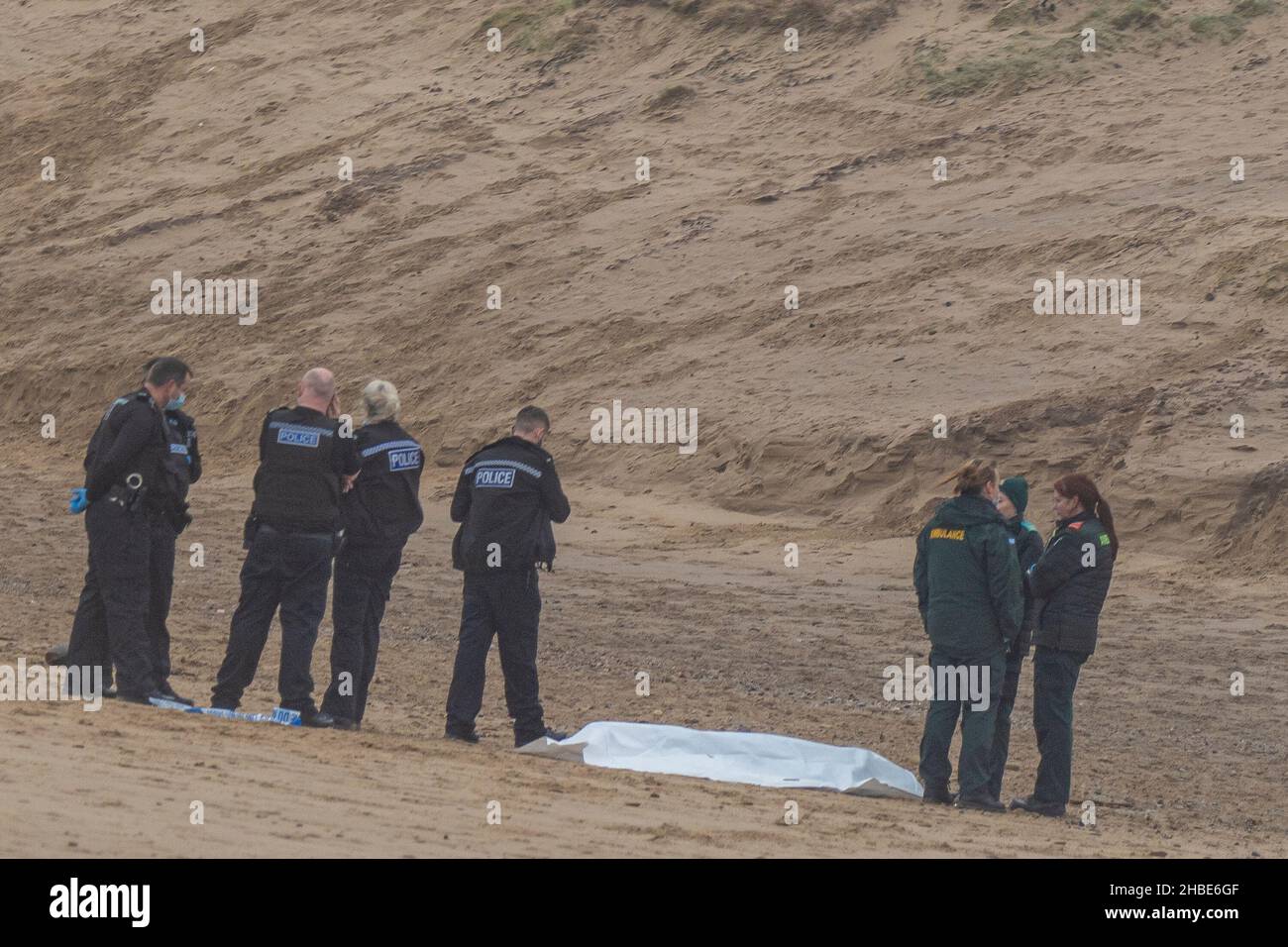 police and ambulance staff stood around a dead body washed up on a ...