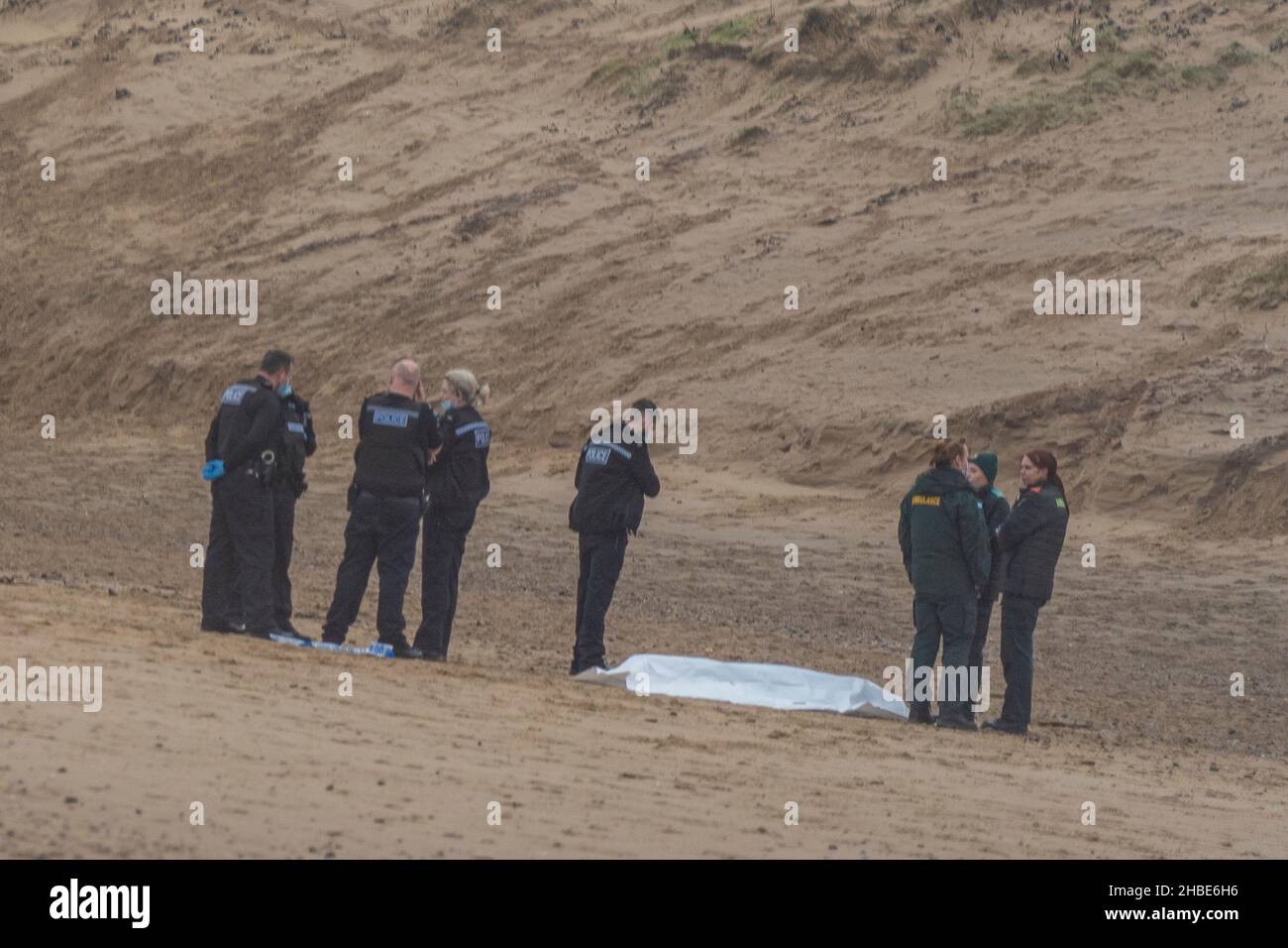 police and ambulance staff stood around a dead body washed up on a ...
