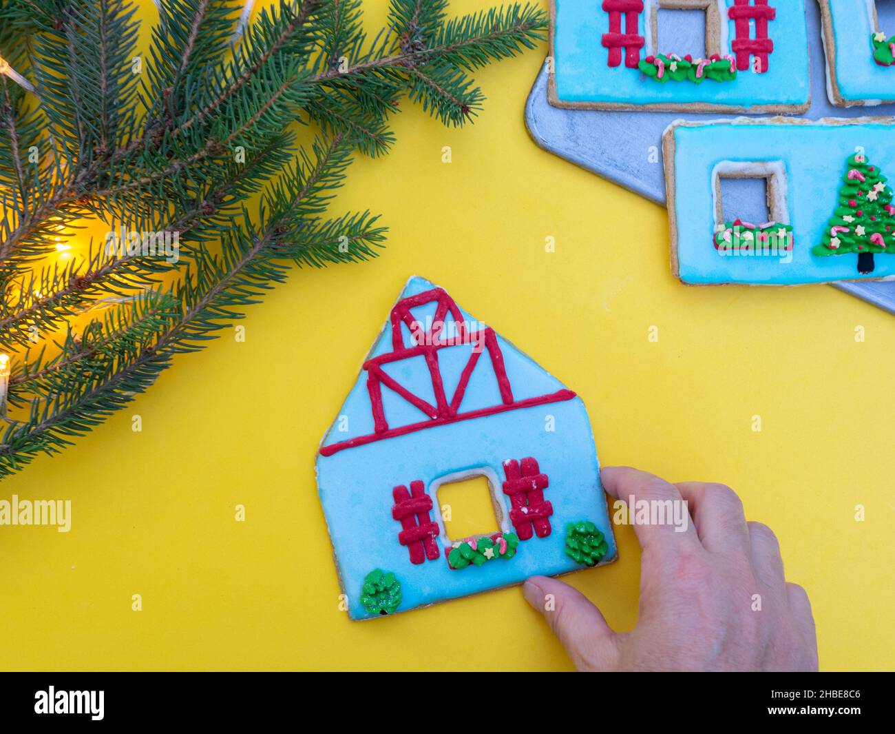 A hand touching a gingerbread house isolated on a yellow background ...