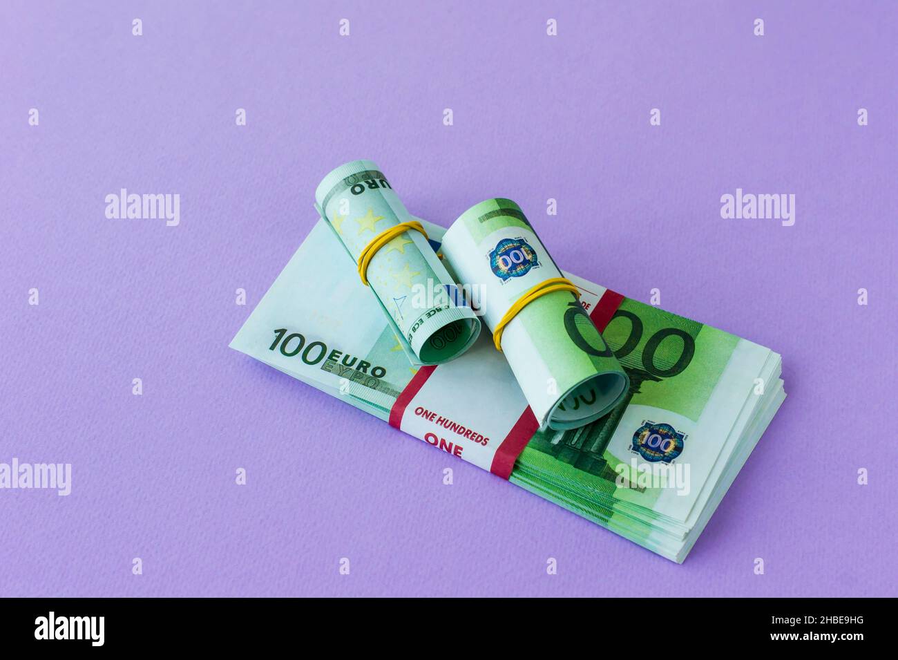 a pack of 100 euro banknotes in a bank package and two rolls under an ...