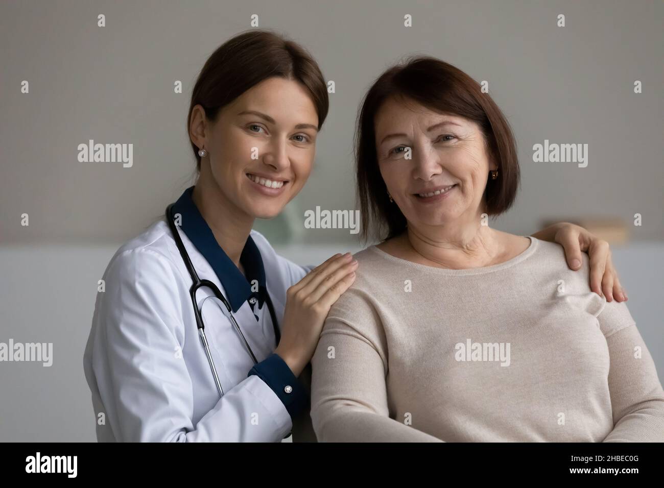 Young female doctor hug shoulders of elderly woman patient pensioner ...