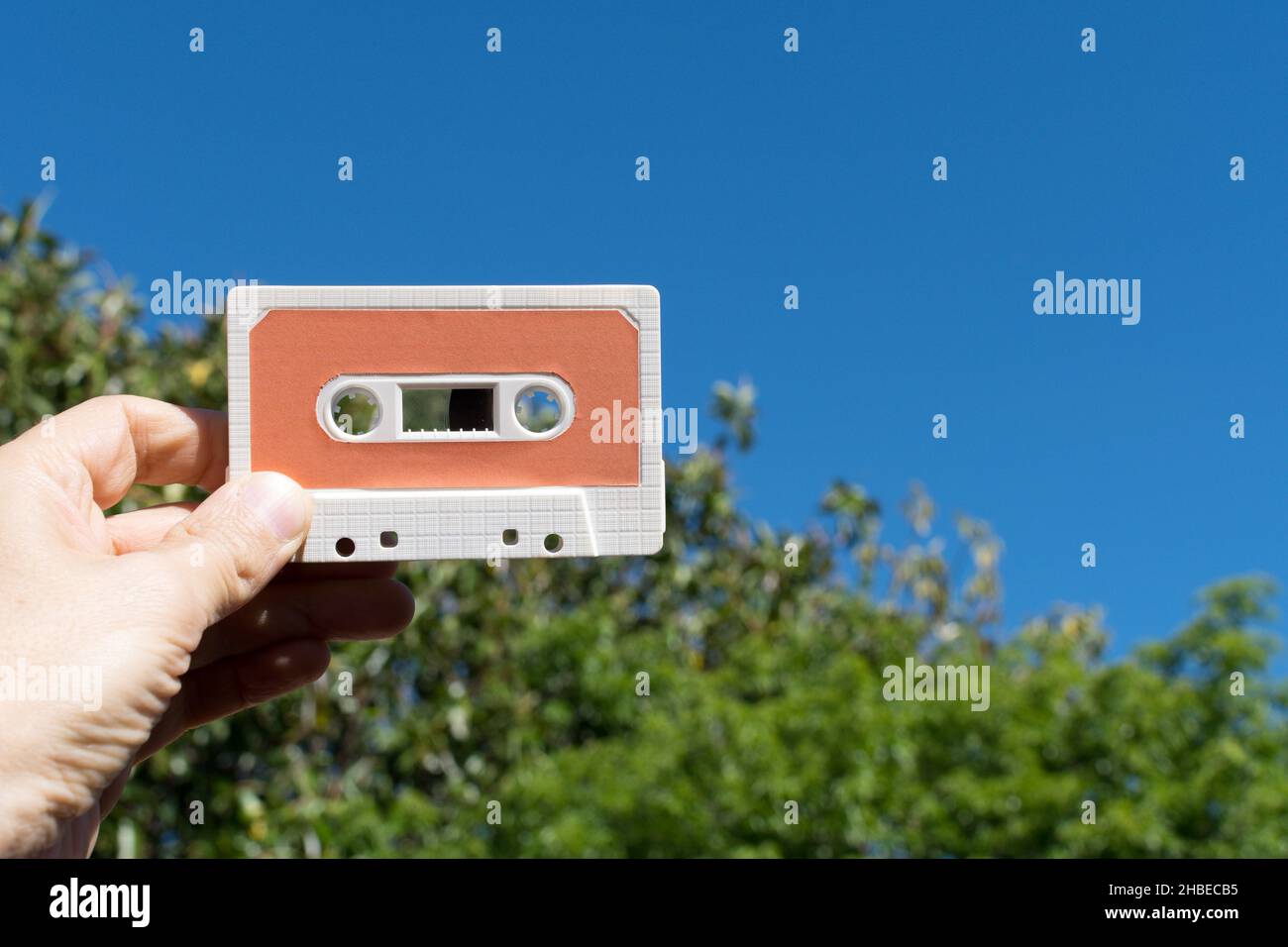 A hand holding an audio cassette outdoors Stock Photo - Alamy