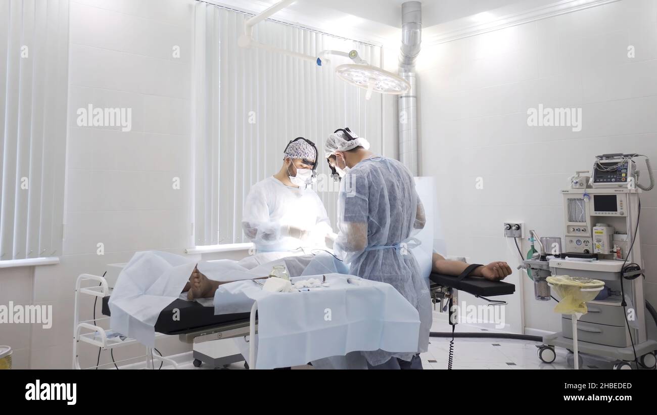 Team of doctors perform surgery while patient is under anesthesia. View ...