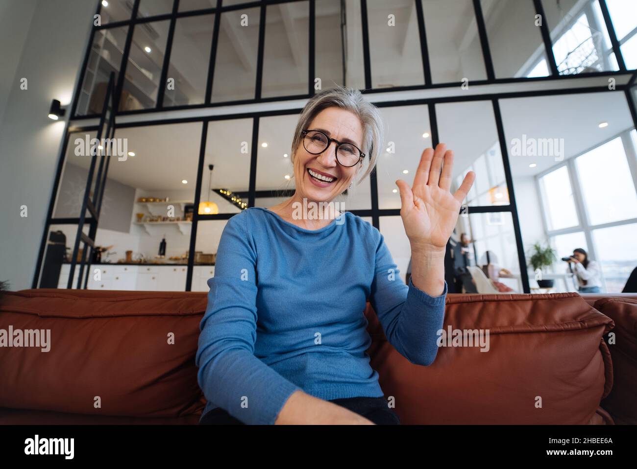 Middle Aged Woman Smiles and Waves to the Camera, Looking at Camera ...