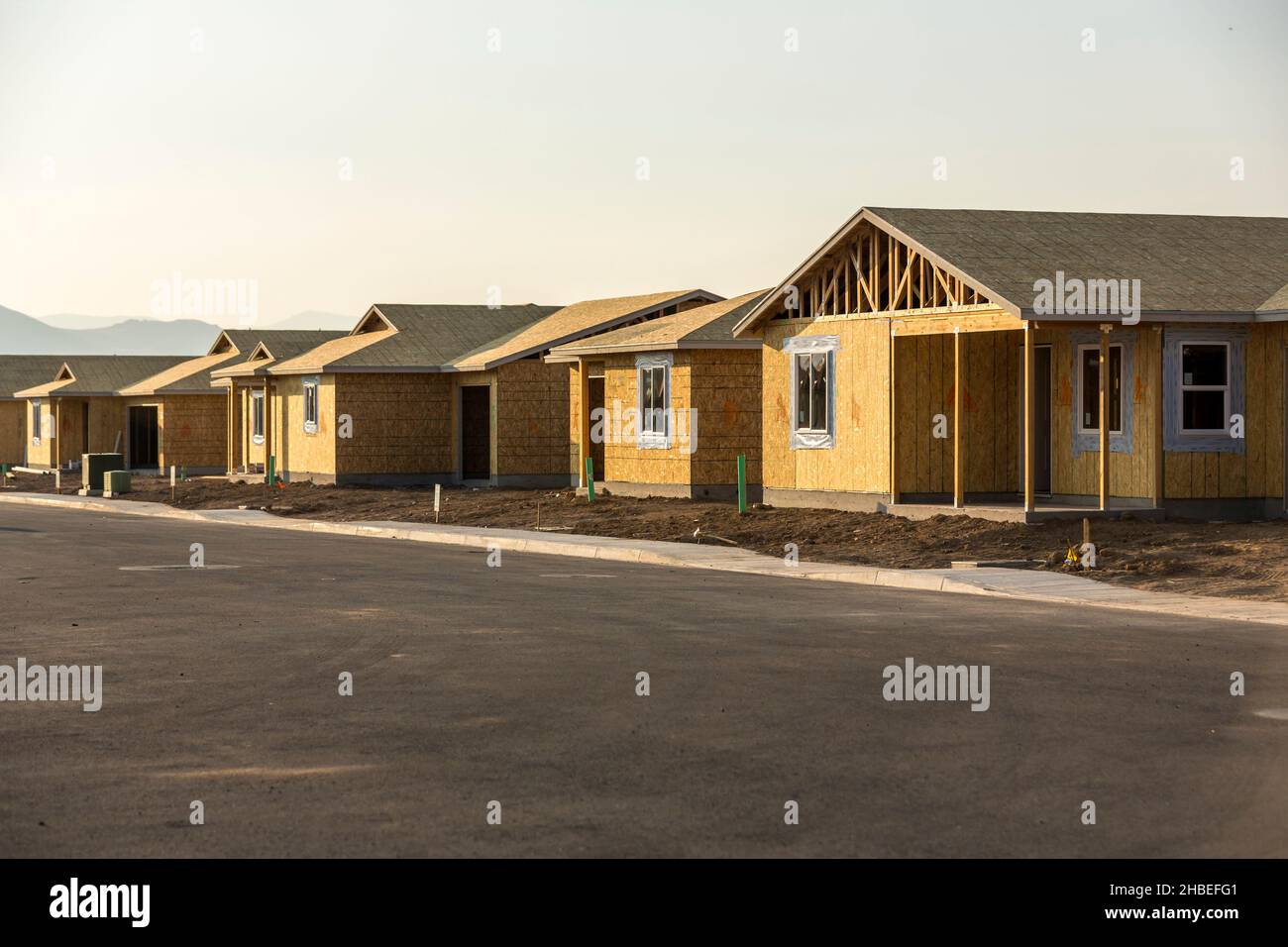 Line of unfinished houses under construction on an empty parking lot ...