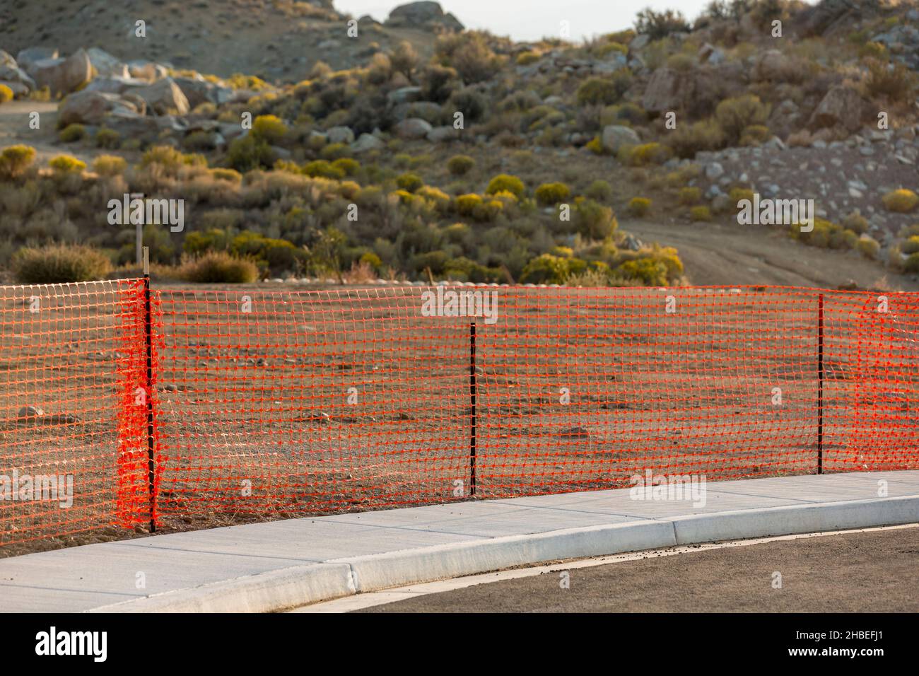 Orange safety fence lines a lot near desert hill Stock Photo - Alamy