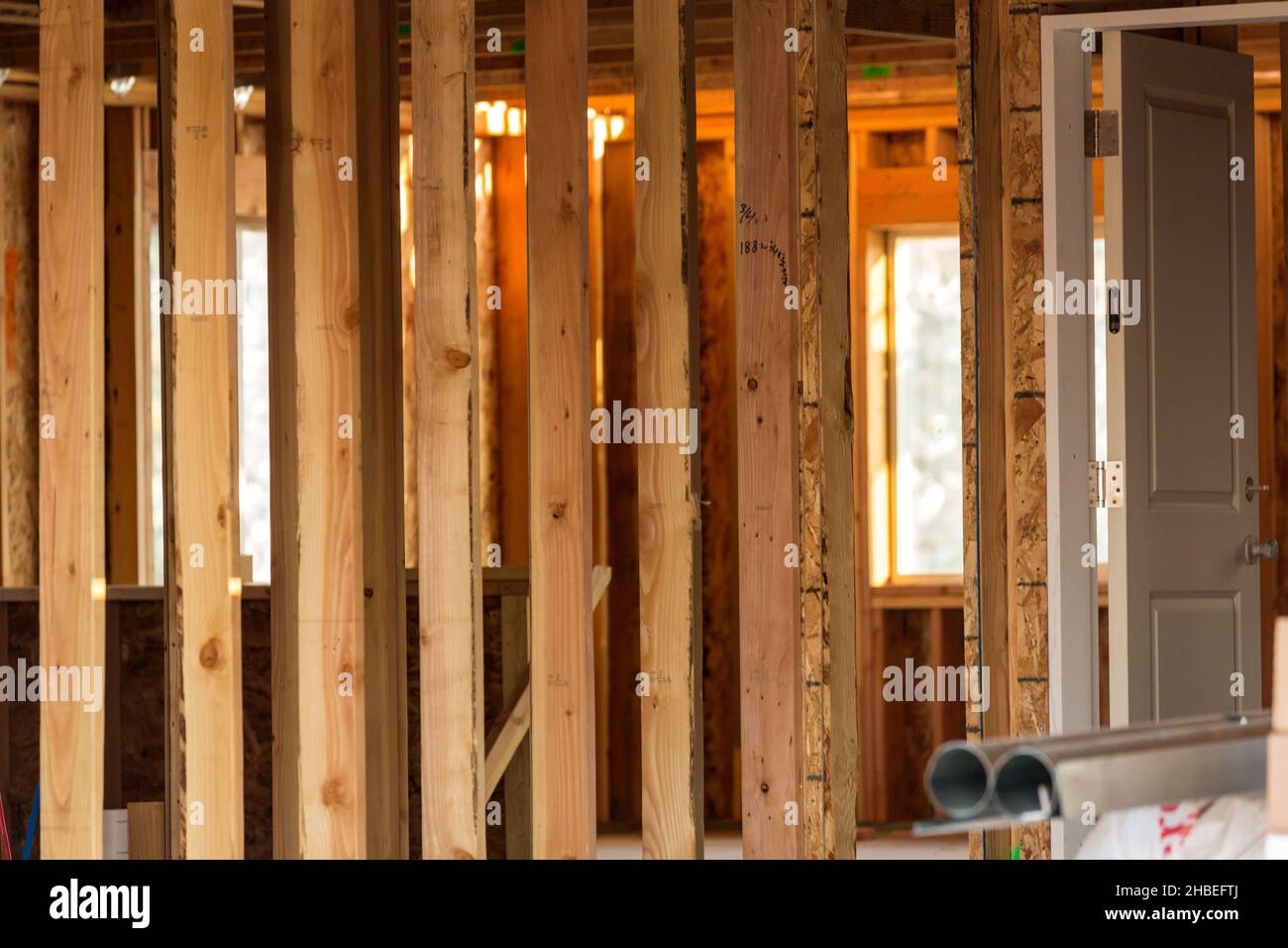 Boards and lumber stand inside the frame of an unfinished house Stock ...