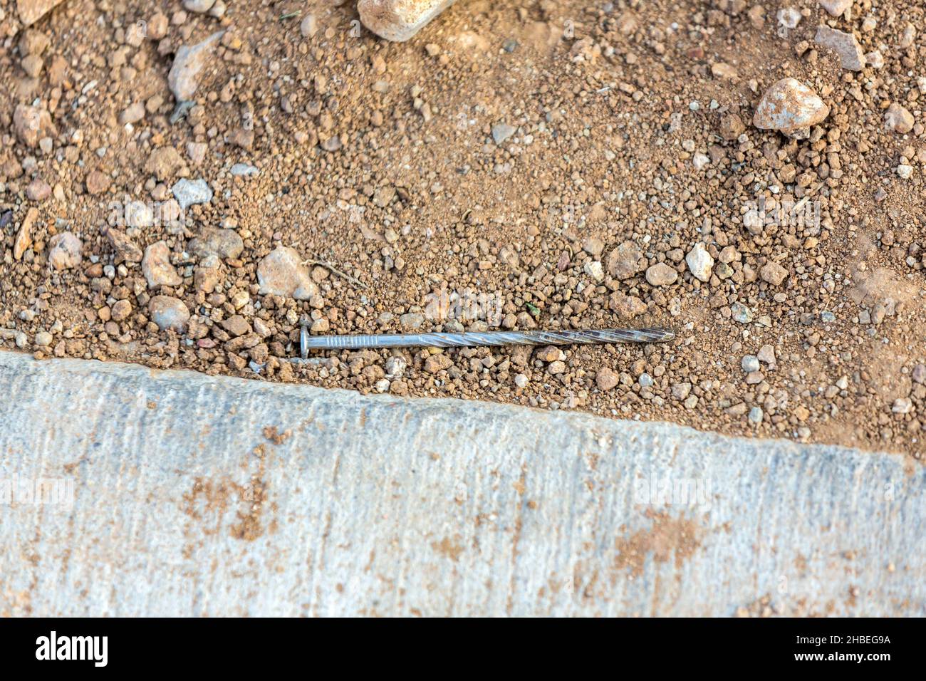 One large framing nail dropped on the ground next to a sidewalk Stock ...