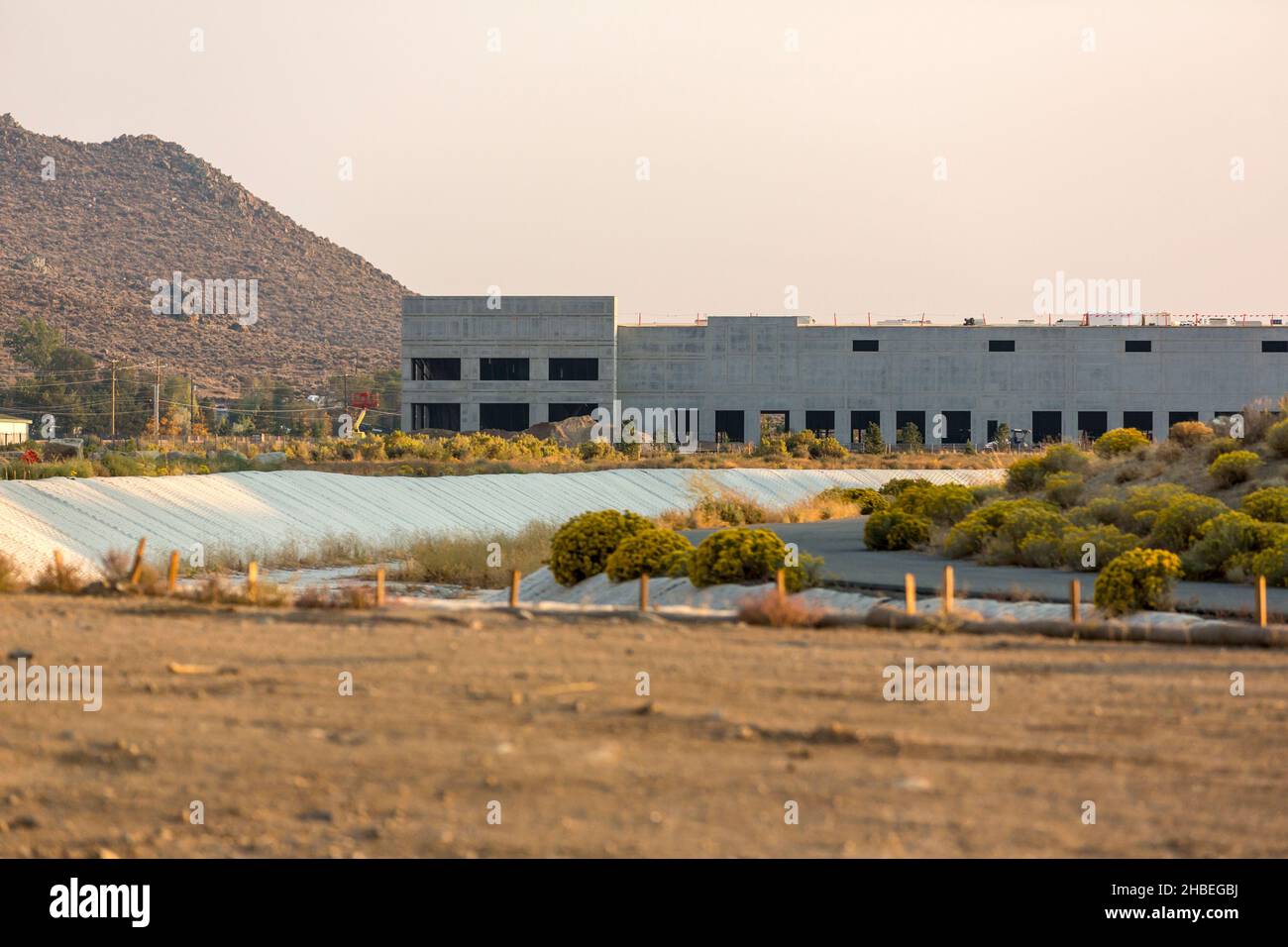 Partially finished warehouse beyond a concrete ditch in the desert ...