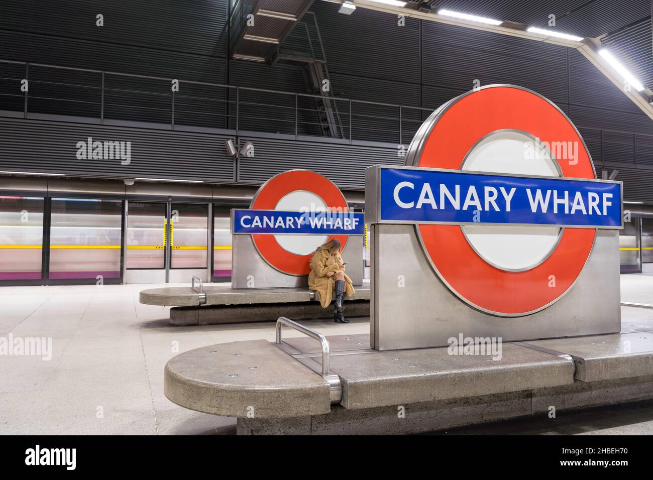 a woman tube passenger sits on station bench waiting for her train at ...
