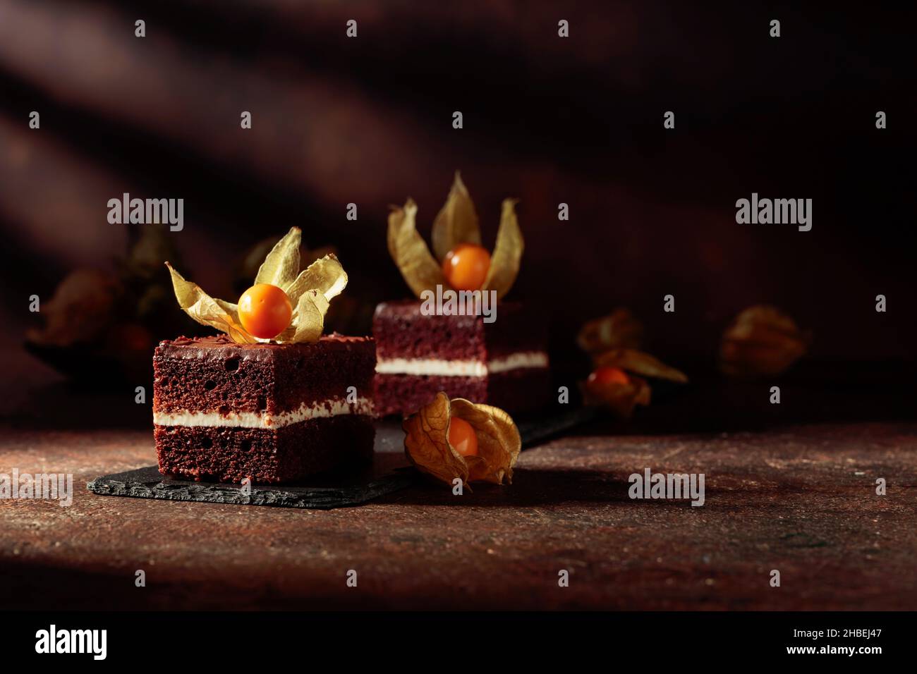 Chocolate cake with physalis on a brown background. Copy space Stock Photo - Alamy