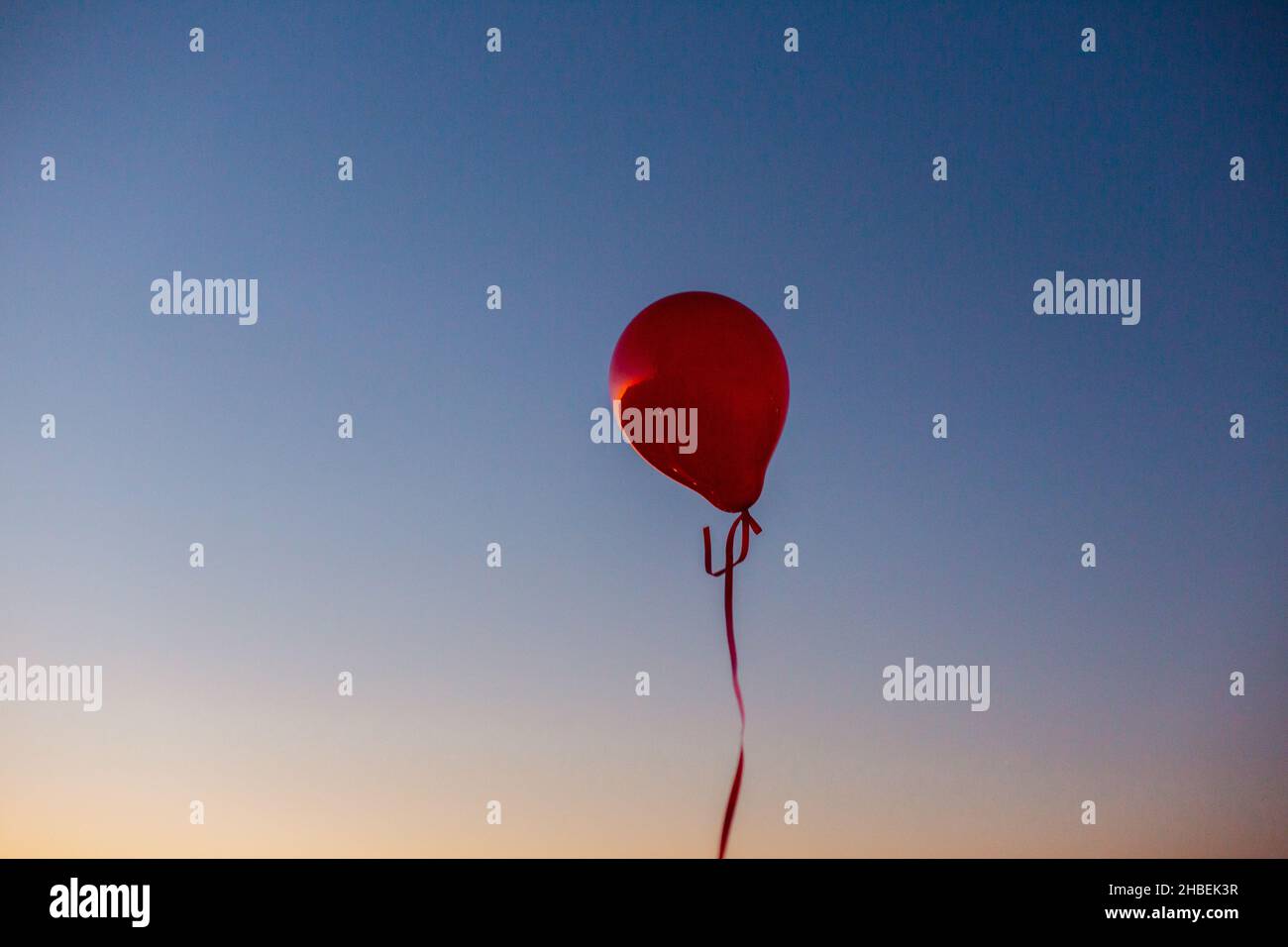 Red balloon floating in the sky at dusk Stock Photo - Alamy